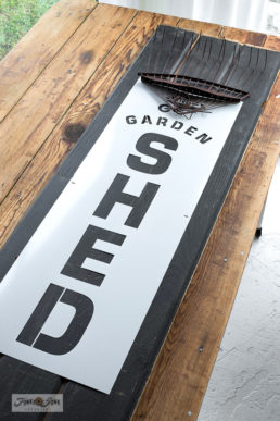 Rustic DIY garden shed sign with a rusty rake